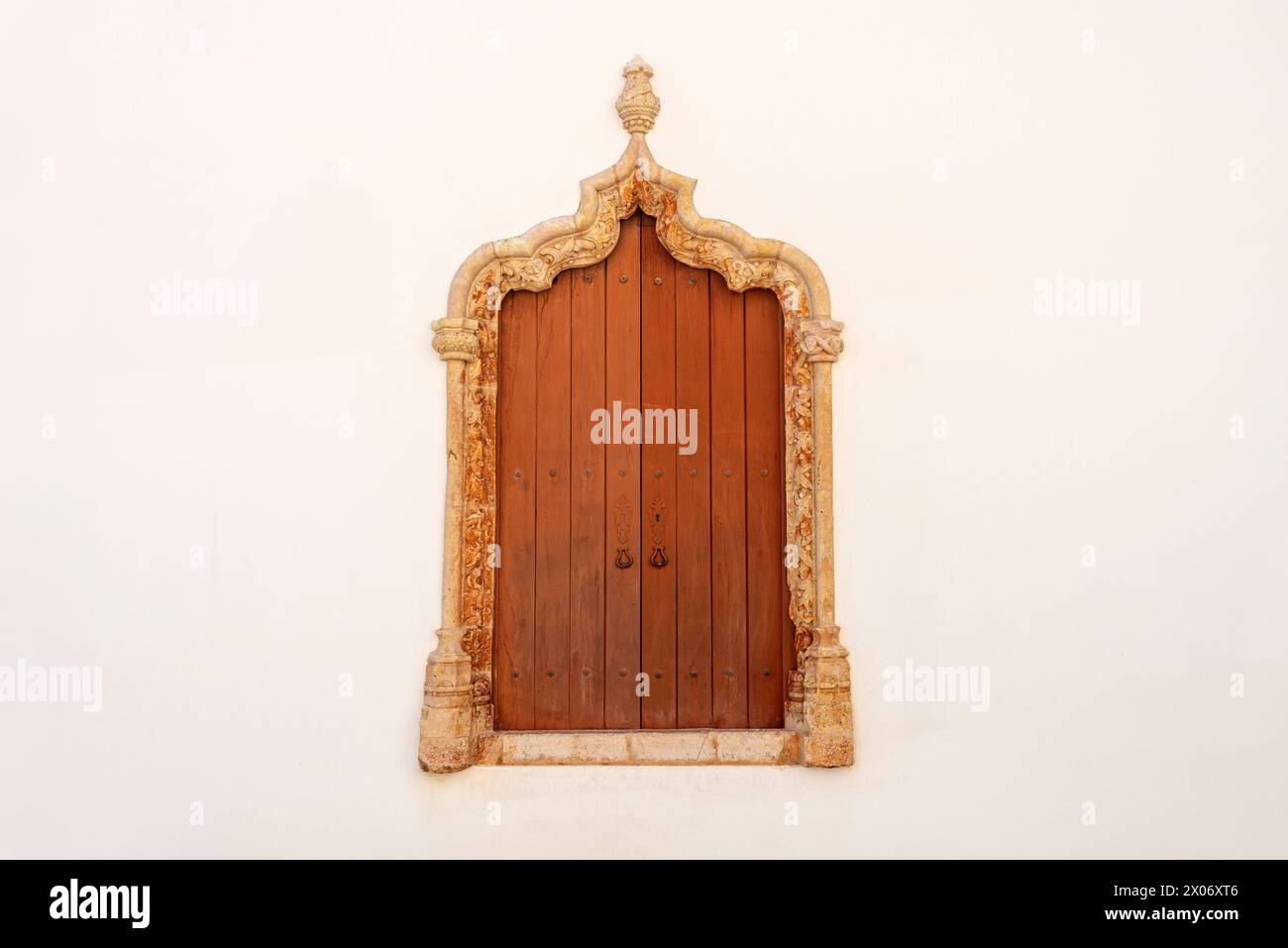 Ornate plaster window frame with closed wooden shutters in a white wall ...