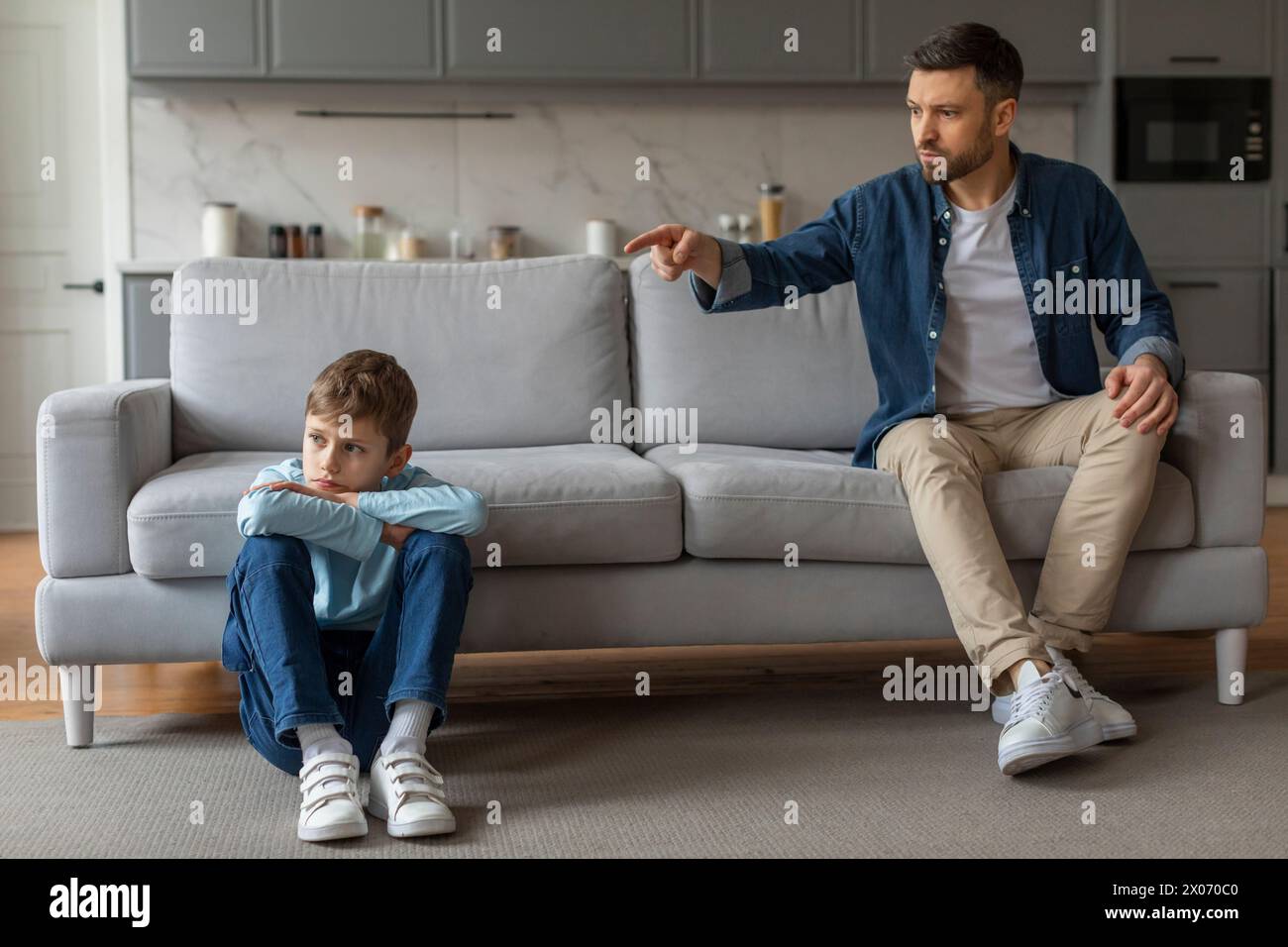 Man scolding a young boy sitting on floor Stock Photo - Alamy
