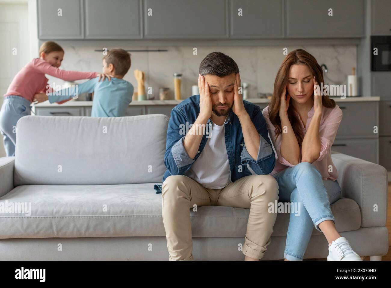 Stressed parents with kids playing in background Stock Photo - Alamy