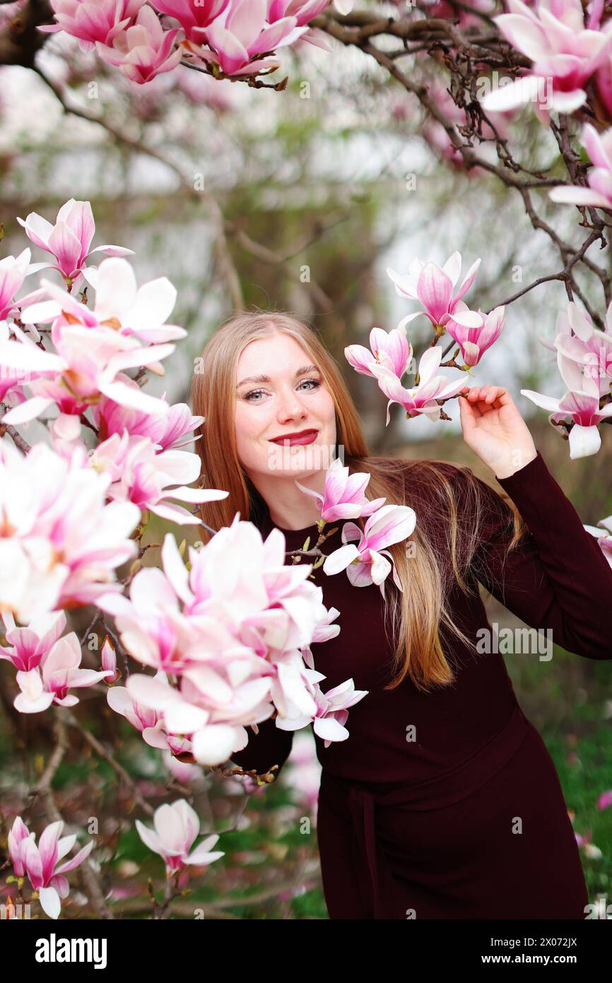 beautiful young girl posing in blooming magnolia Stock Photo - Alamy
