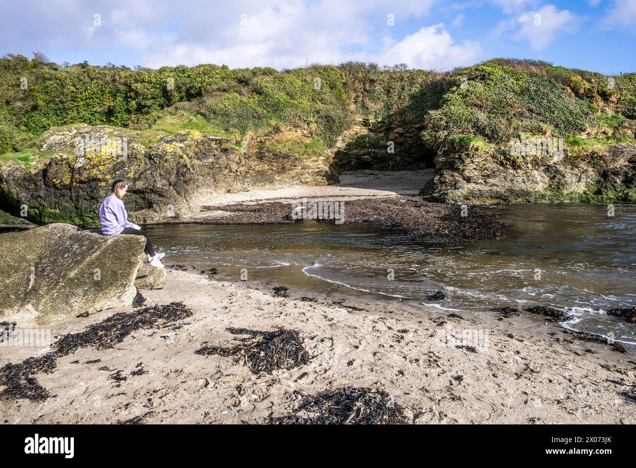 A young teenage female girl sitting alone on a rock by Par River ...