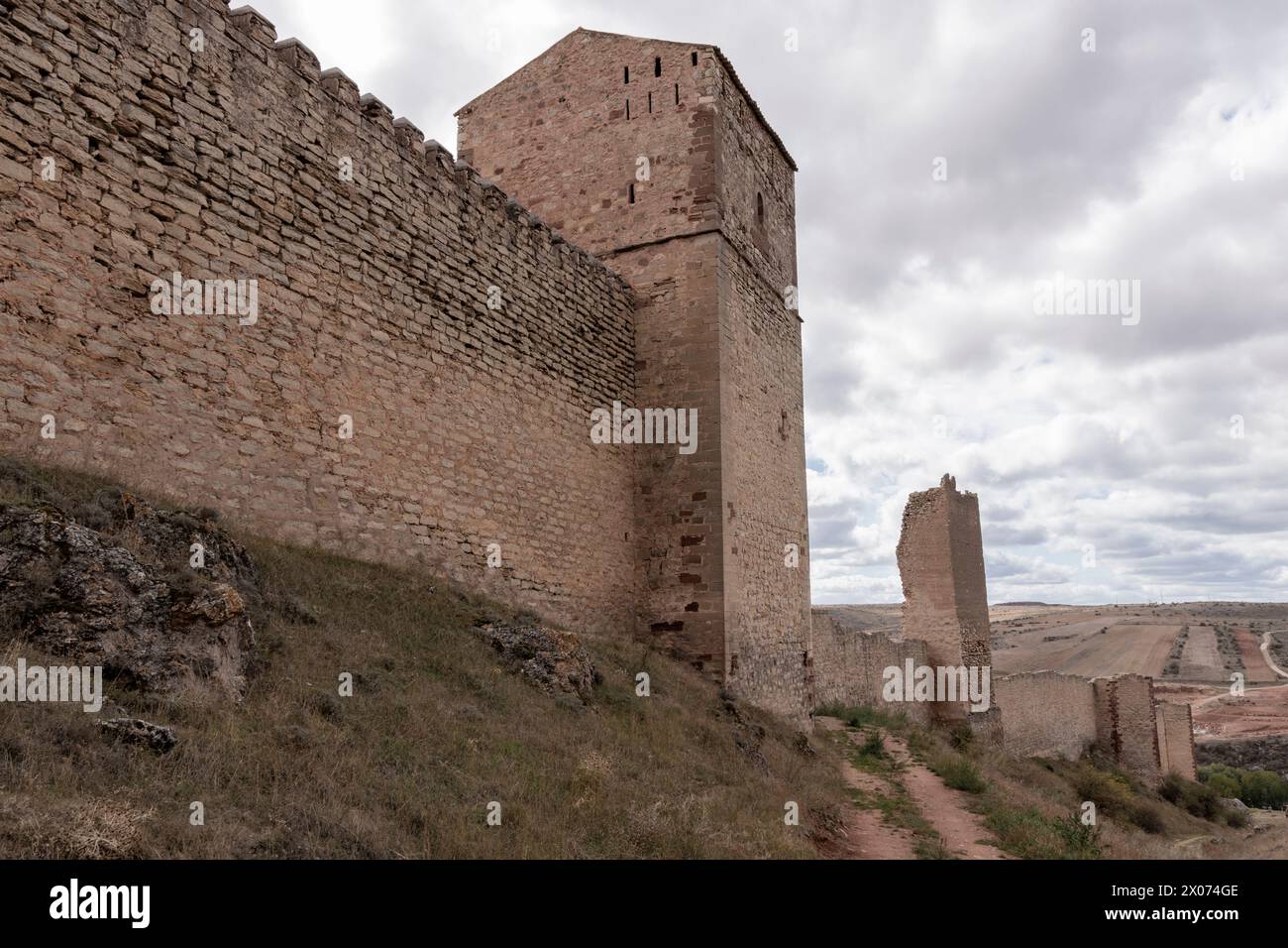 ancient, tall stone wall and tower, part of a fortress, under a cloudy ...