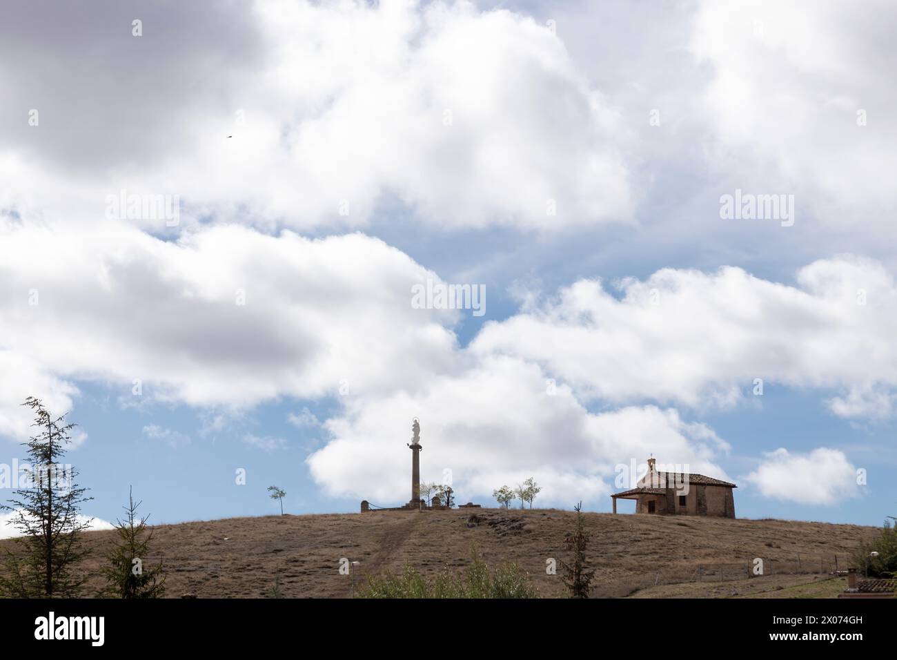 a small stone building and tower atop a barren hill under a sky dotted ...