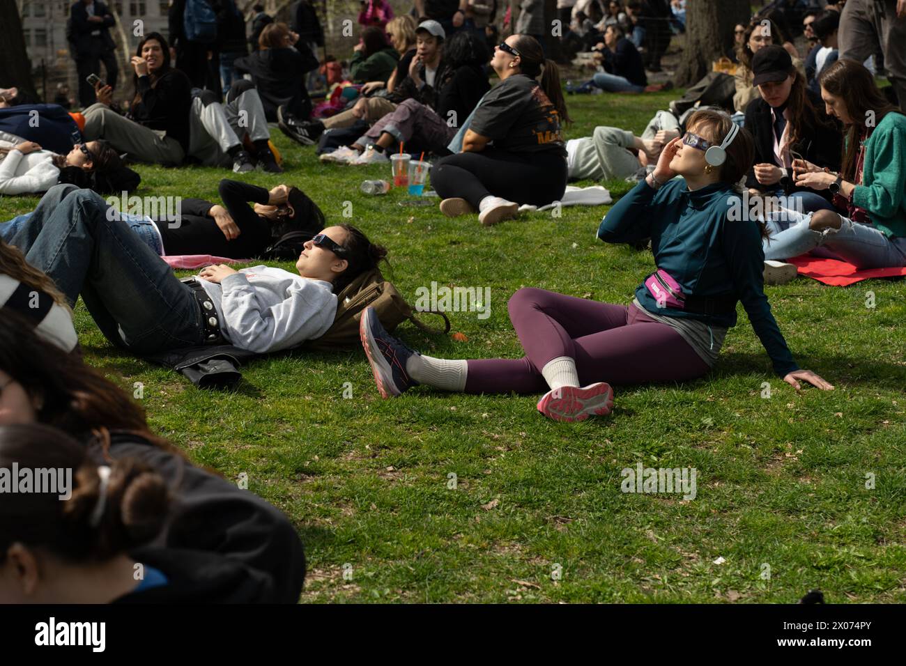 A woman with headphones on and people laying down watch the 2024 Solar ...