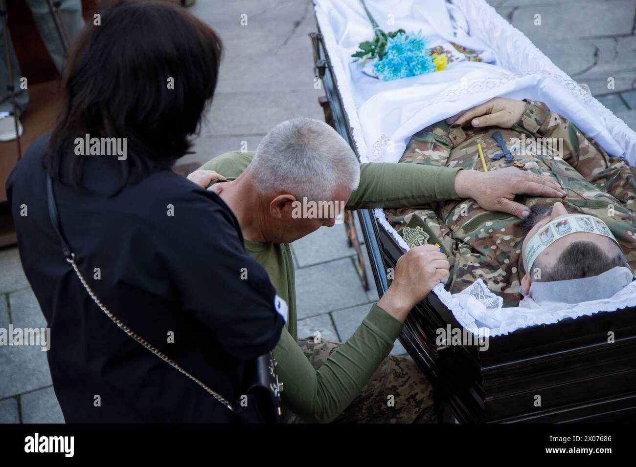 KYIV, UKRAINE - APRIL 9, 2024 - A man kneels at a coffin during the ...