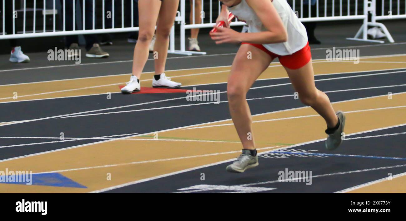 Female runner on an indoor track starting a relay race in her lane ...