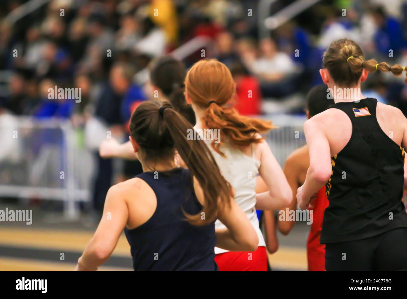 Rear view of girls running in a one mile race on an indoor track Stock ...