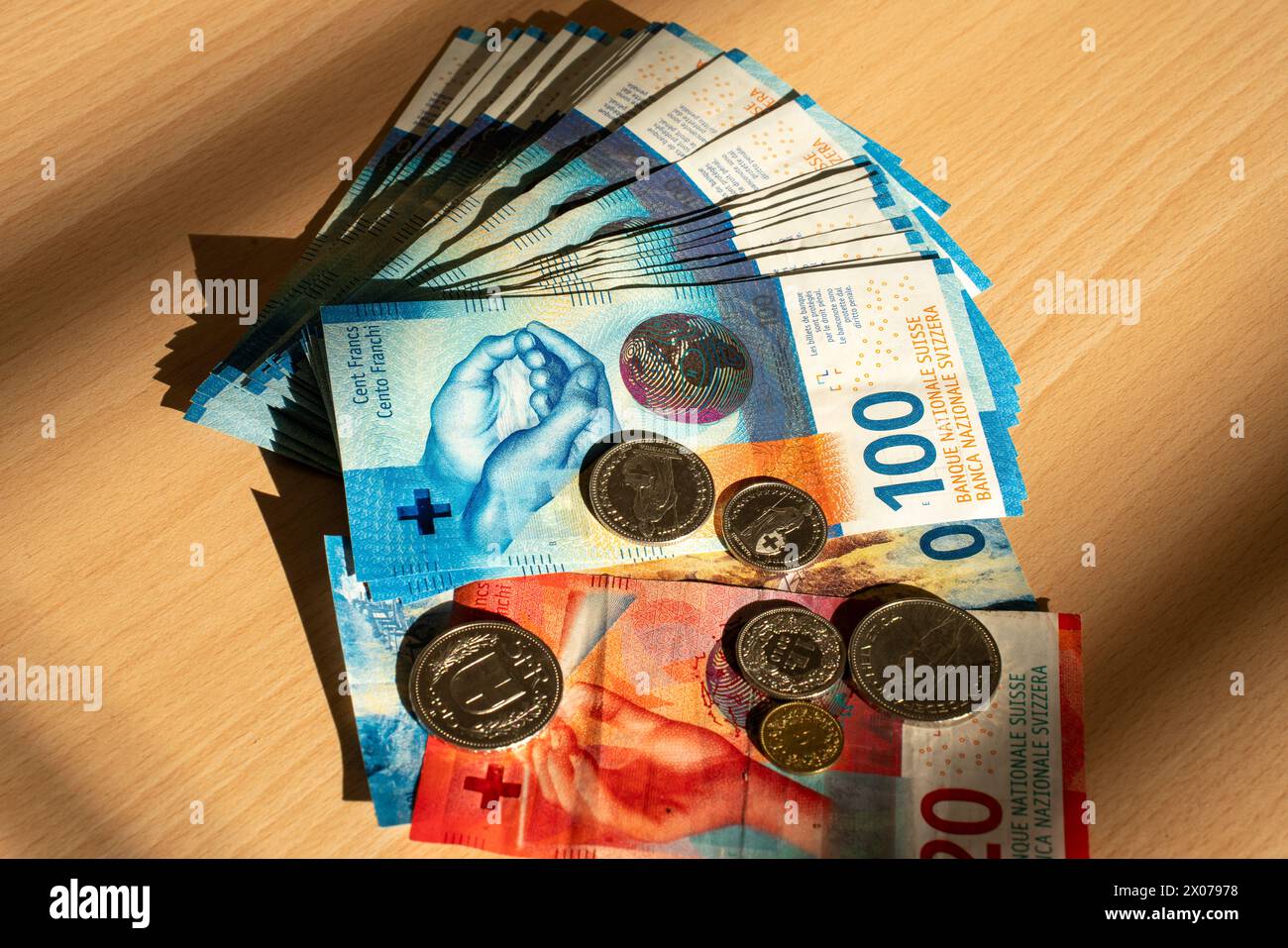 Stack of money, hundred bills, one twenty and coins, lying on a sunlit ...