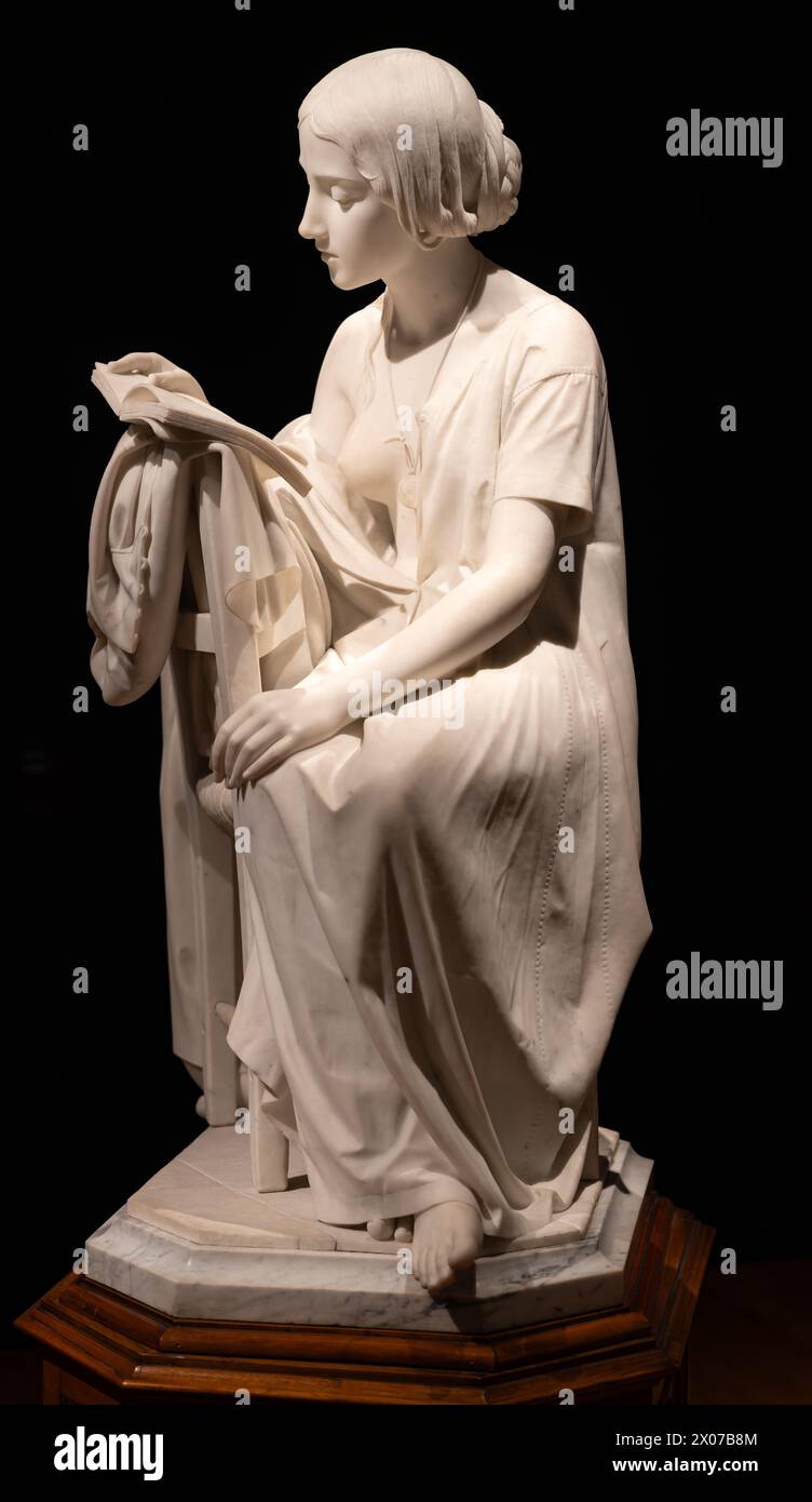 Side view of Marble statue of girl reading a book on clothes hanged on ...
