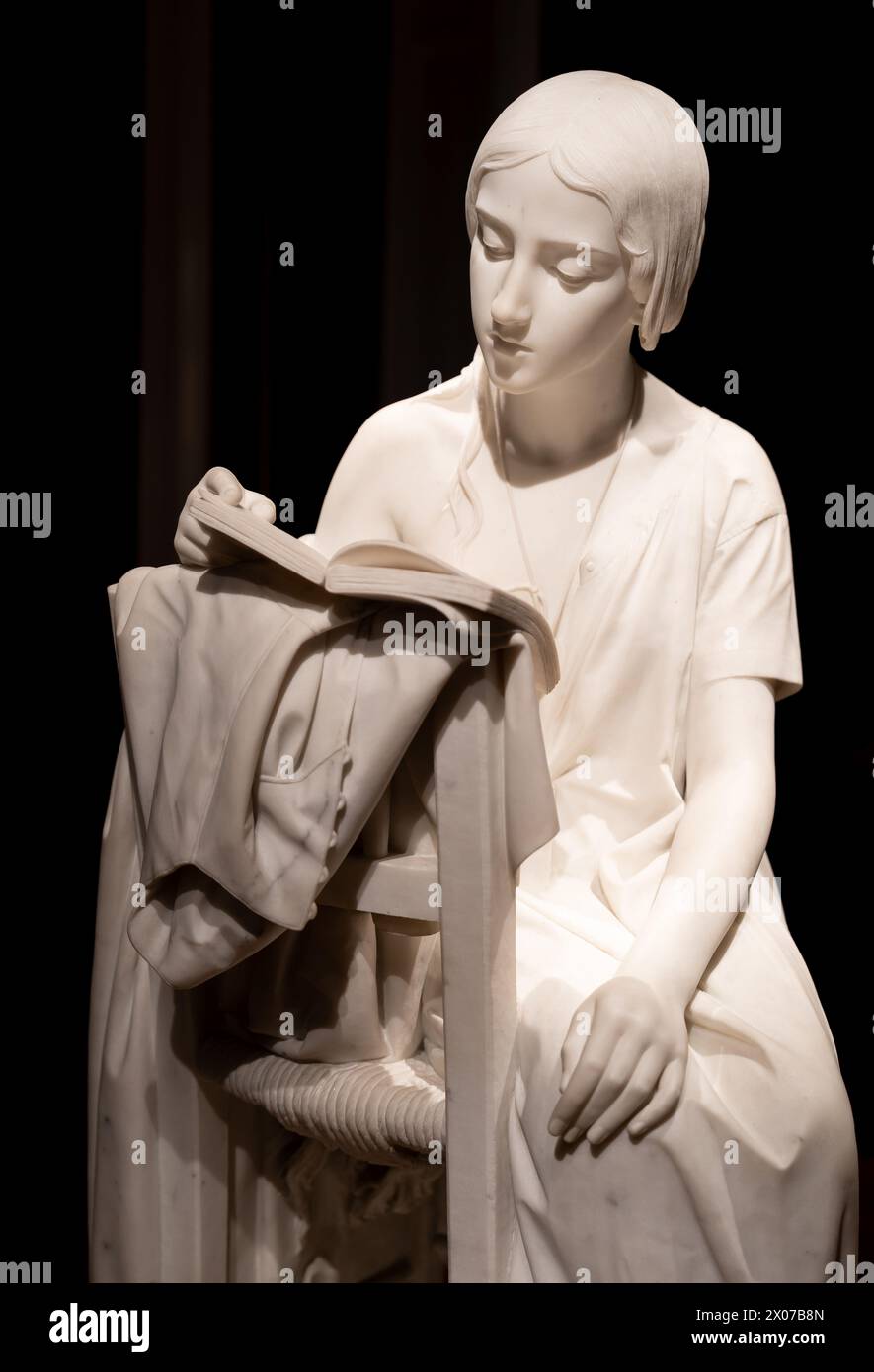 Marble statue of girl reading a book on clothes hanged on the back of a ...