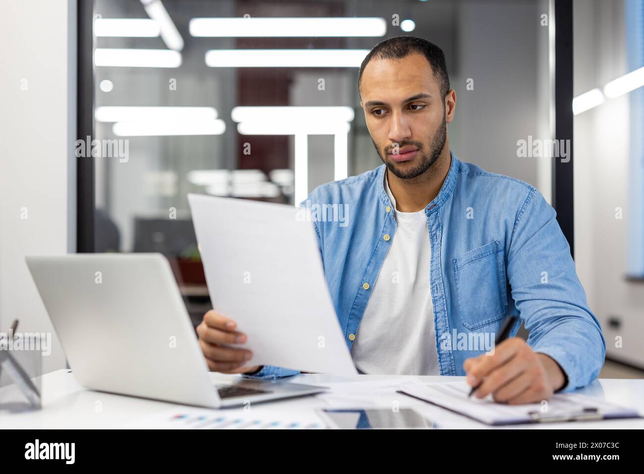 Focused Indian businessman reviewing documents while working remotely ...