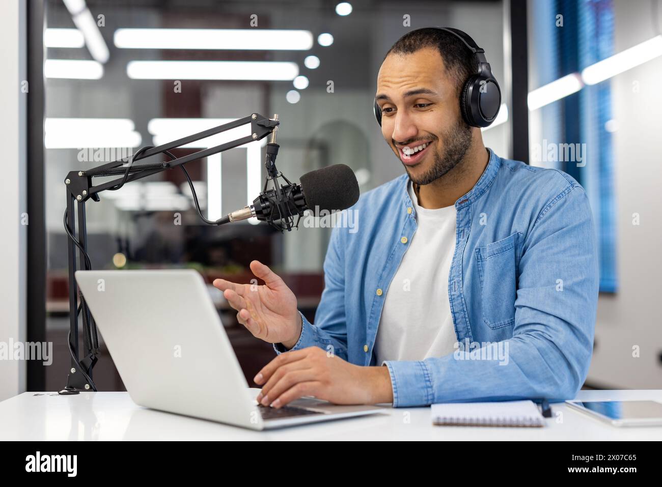Focused Indian man records a podcast from his stylish living room ...