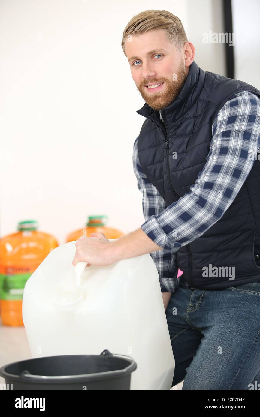male worker putting liquid in big container Stock Photo - Alamy