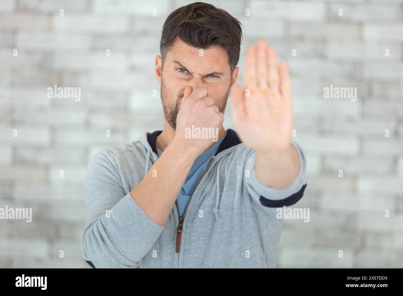 man pinching nose and making gesture to stop Stock Photo - Alamy