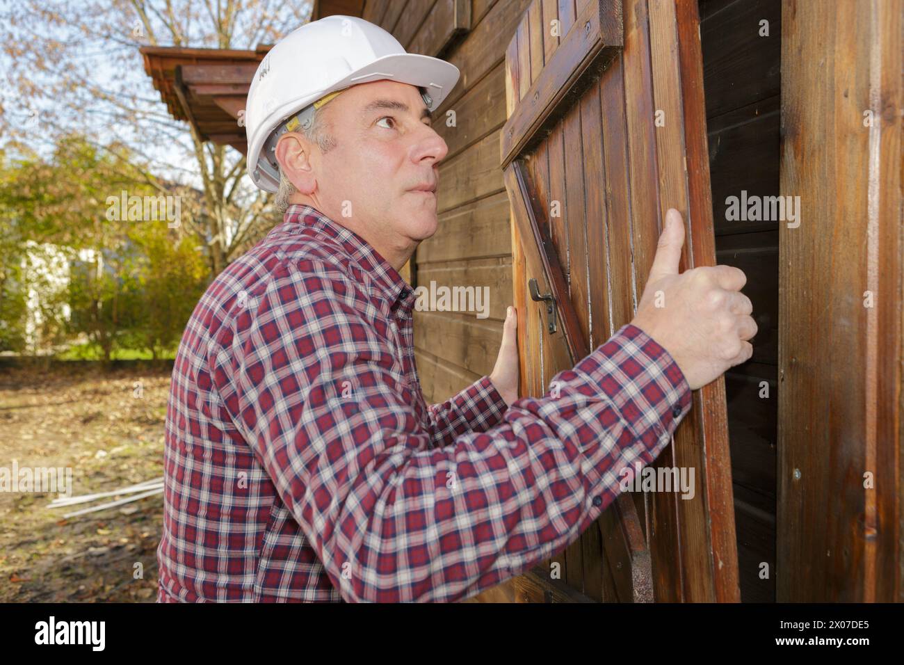 shutter installer fixing barn door Stock Photo - Alamy