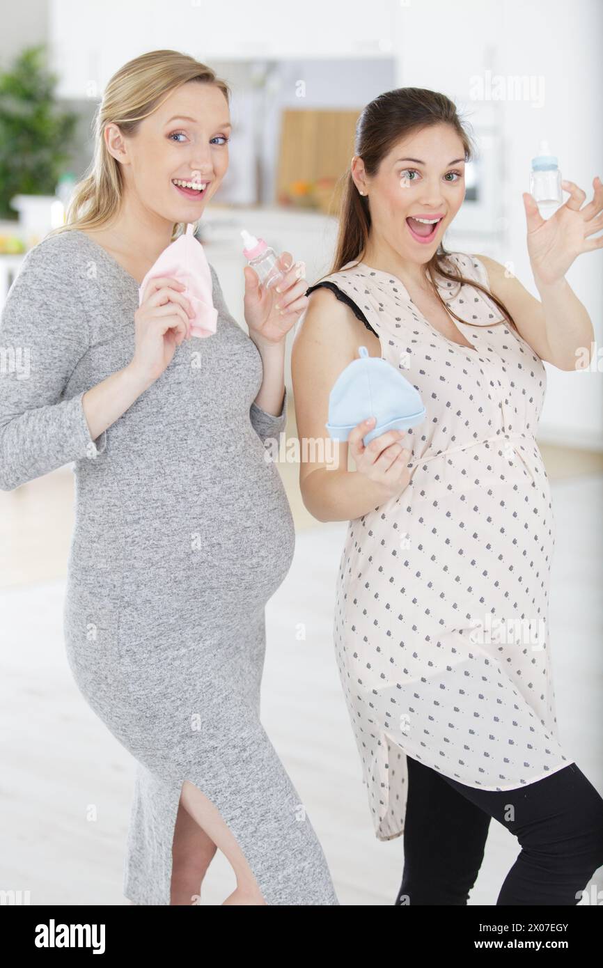 two pregnant women holding baby stuff Stock Photo - Alamy