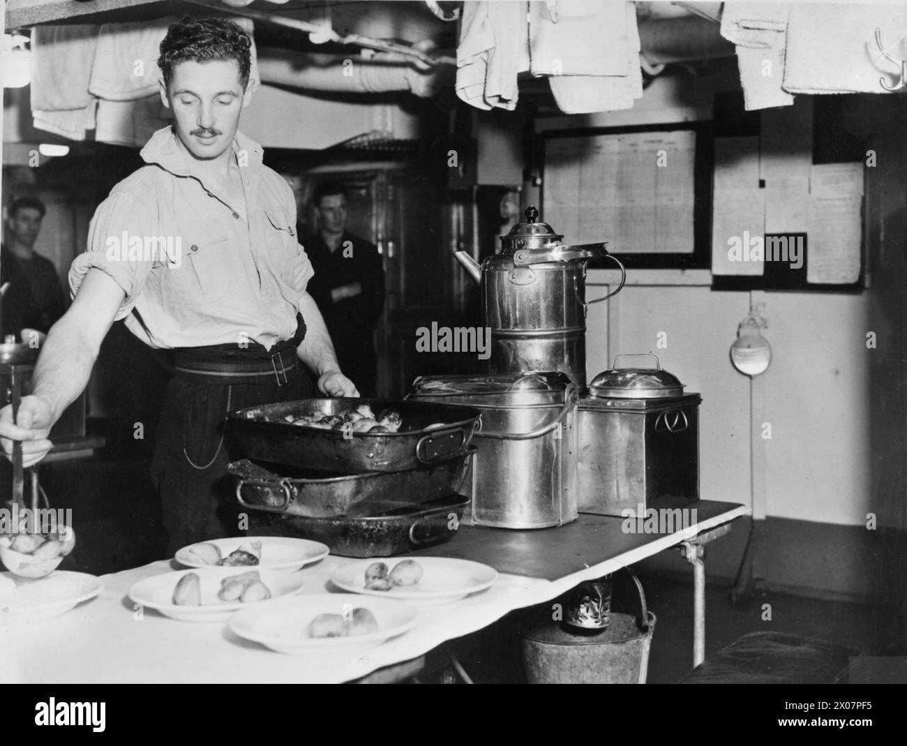 A Marine cook serves dinner to his messmates aboard Kent-class cruiser ...