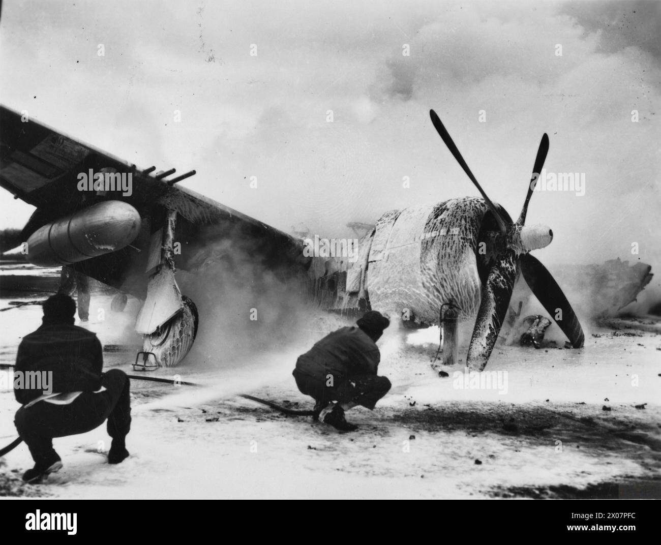Ground personnel of the 56th Fighter Group extinguish a burning P-47 ...