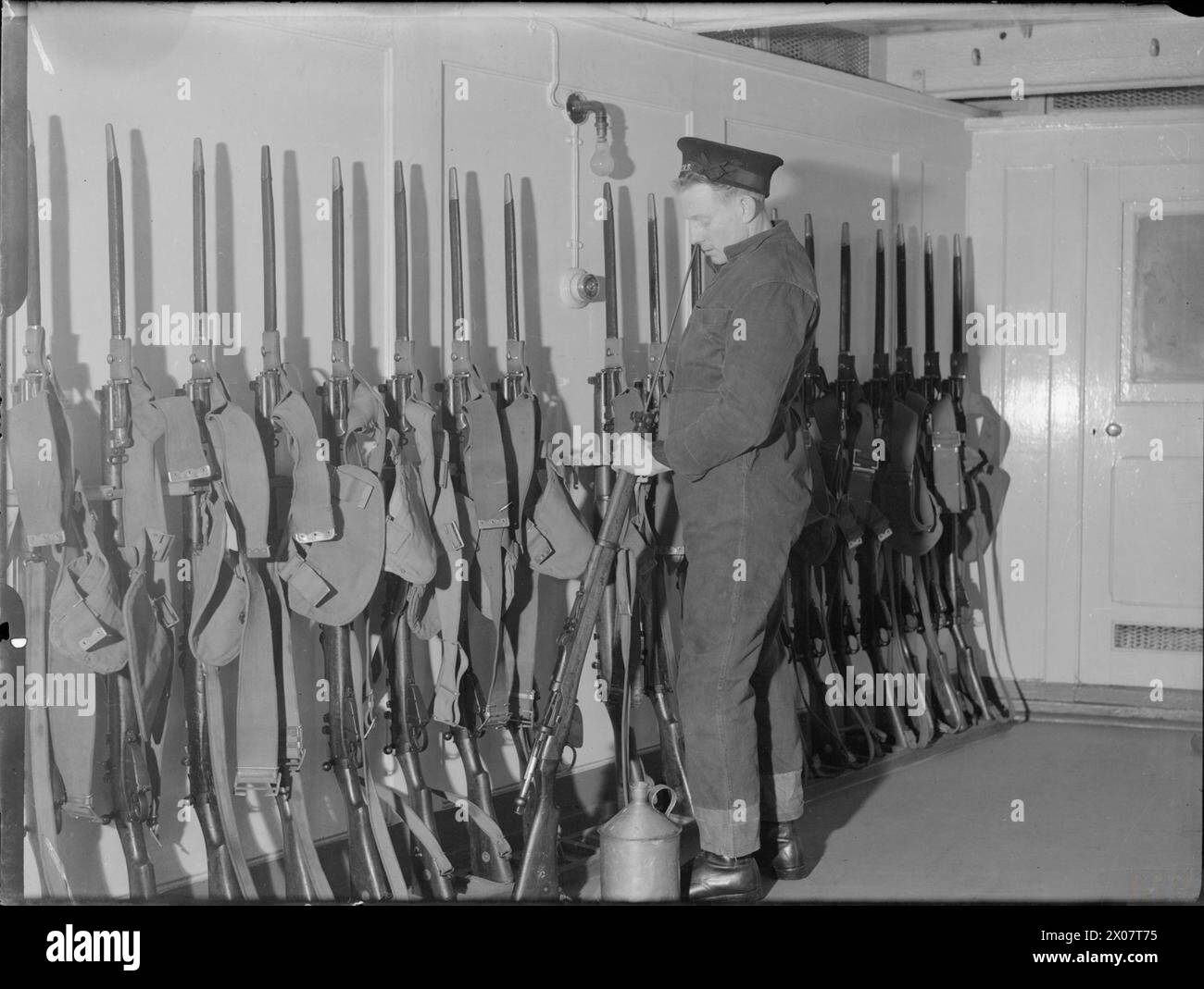 Able Seaman Joe W Scotcher cleans rifles in the armoury on board a ...