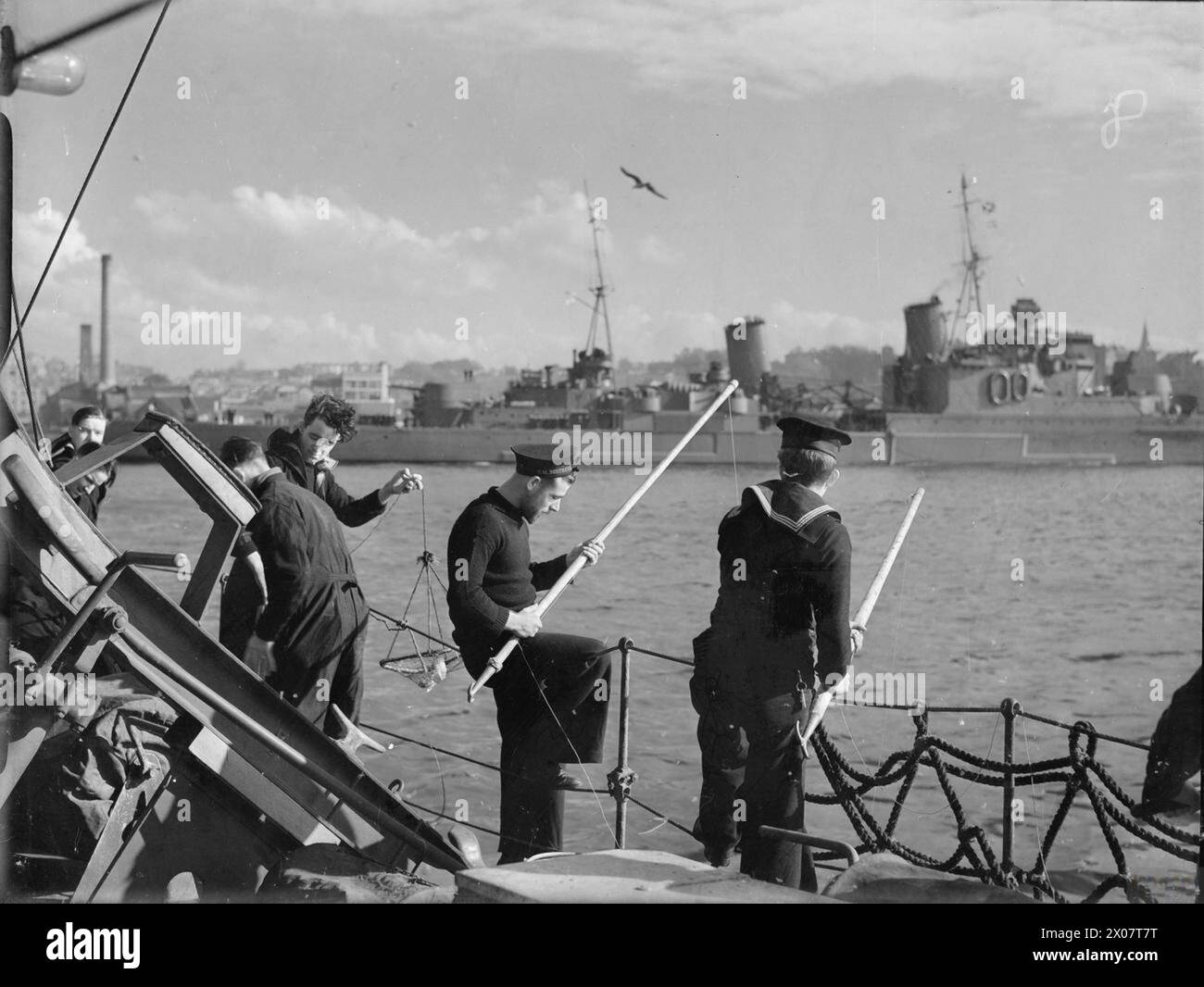 In 1940, sailors aboard the destroyer HMS Kelvin are pictured at anchor ...