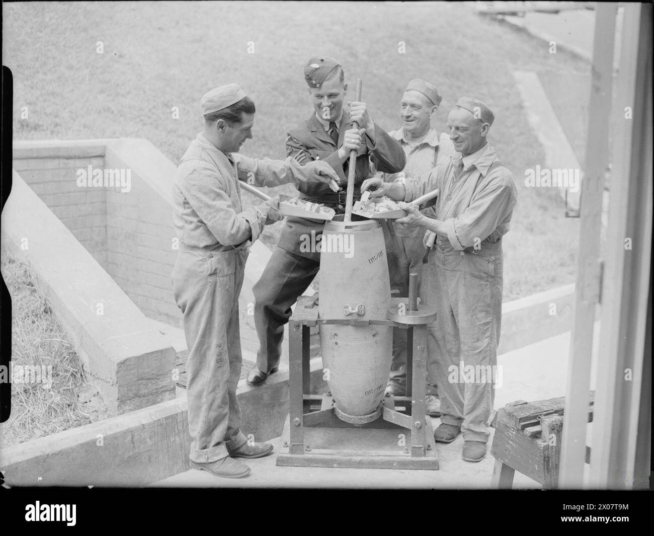 RAF CREWS VISIT A MUNITIONS FACTORY, UK, 1941 - Sergeant T Baxter helps ...