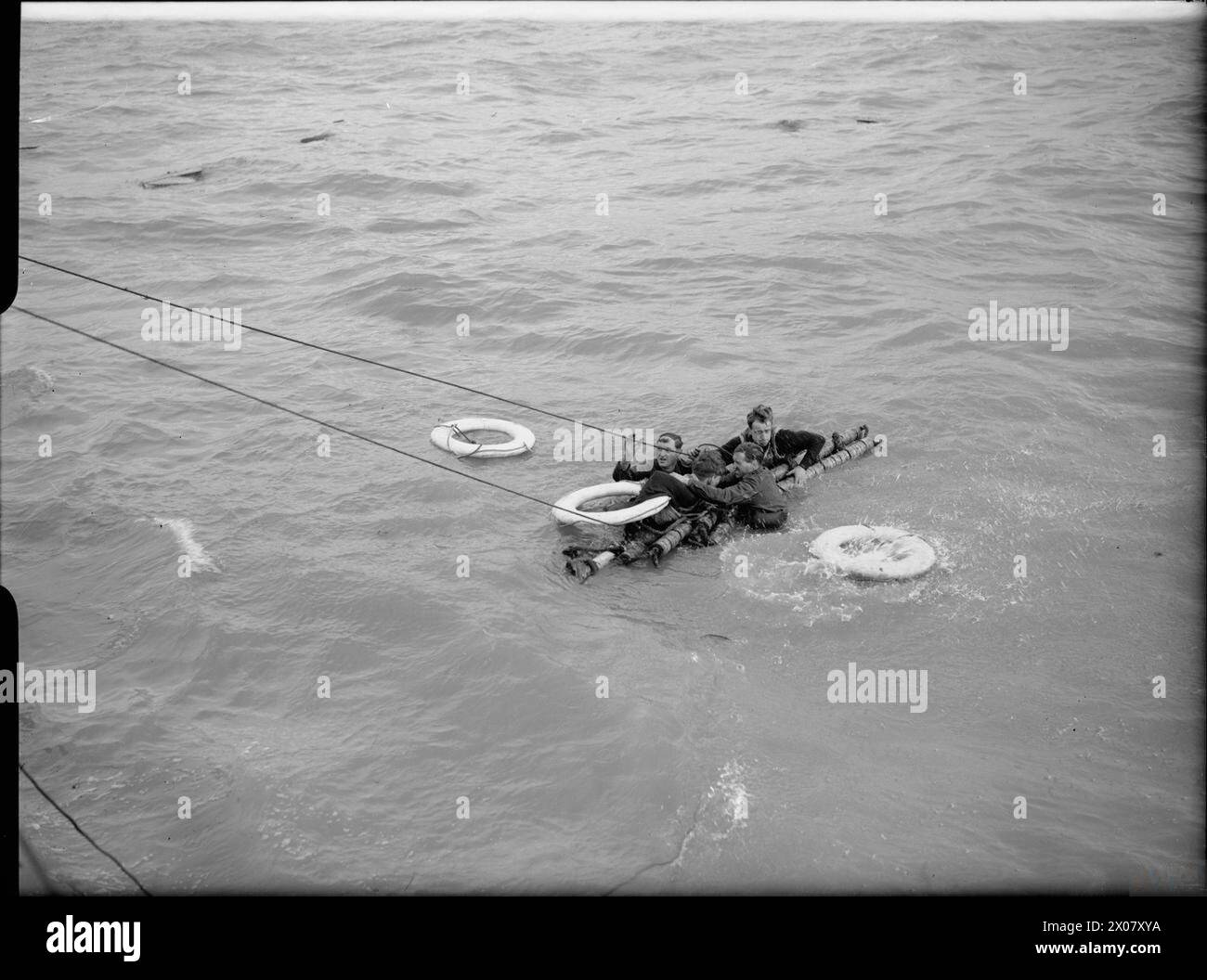 Survivors from a landing craft are clinging to a raft while being ...
