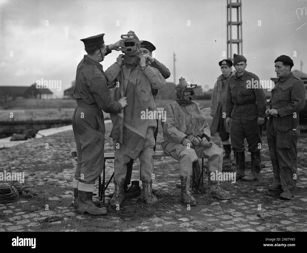 Royal Navy divers are prepared for lowering to explore a dock bed while ...