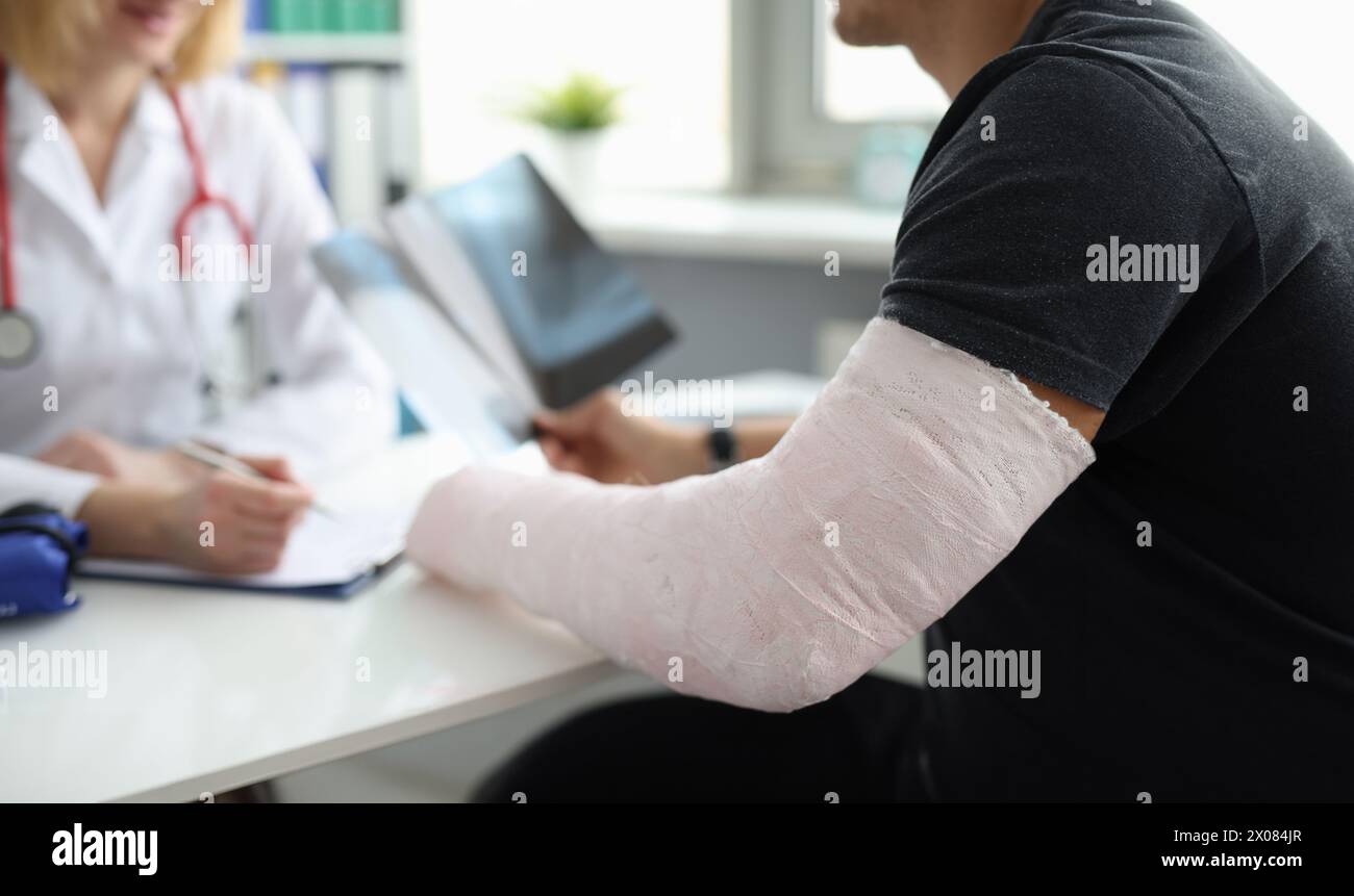 Doctor conducts medical consultation with patient with cast on arm ...