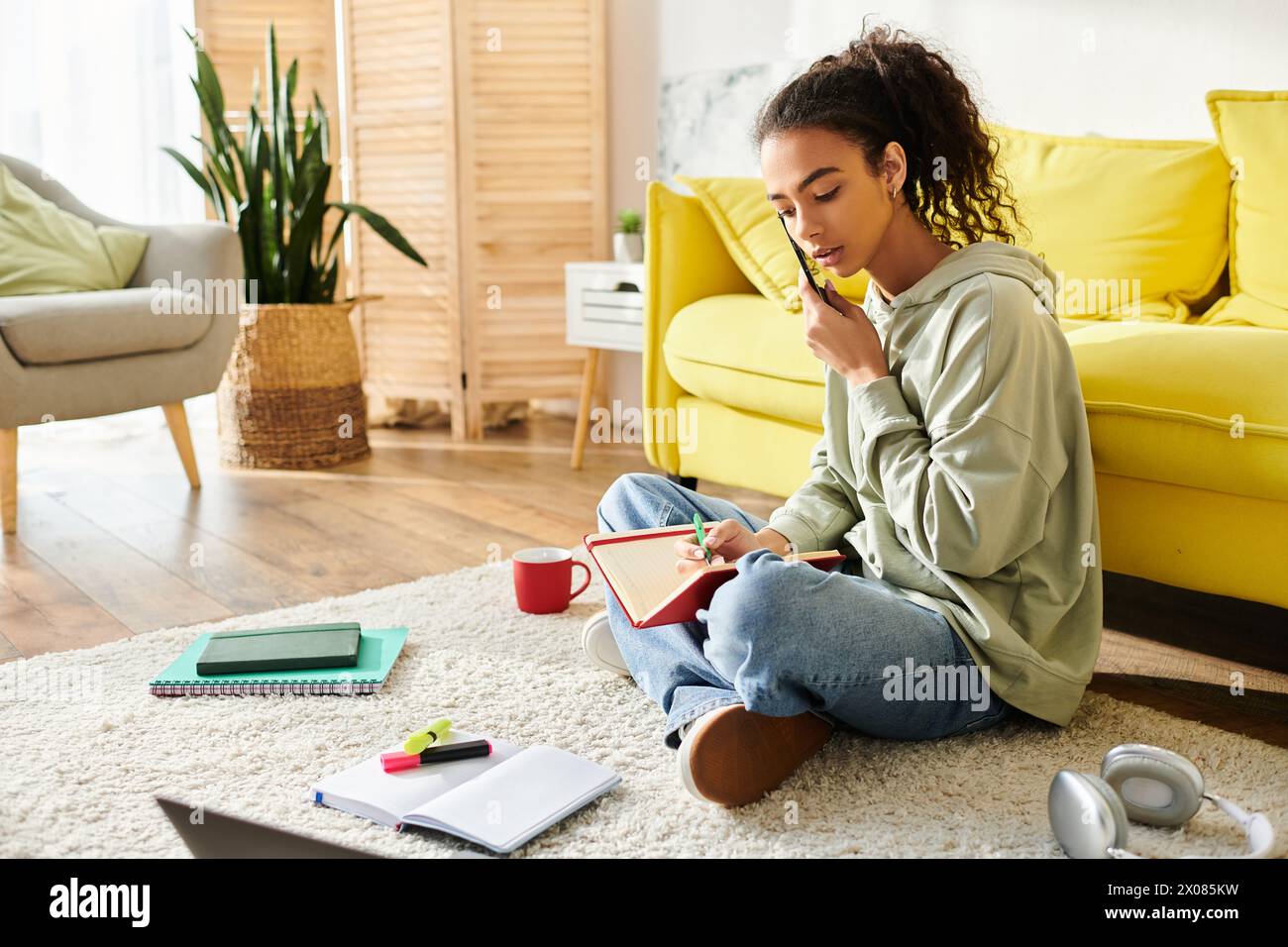 A teenage girl sitting on the floor, using a cell phone for e-learning, fully engaged in virtual ...