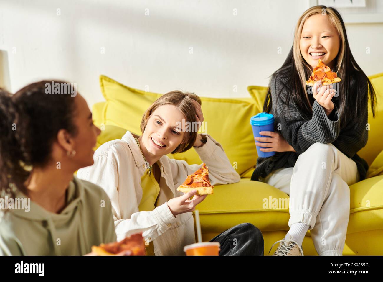 A Diverse Group Of Teenage Girls Sit Together On A Vibrant Yellow Couch