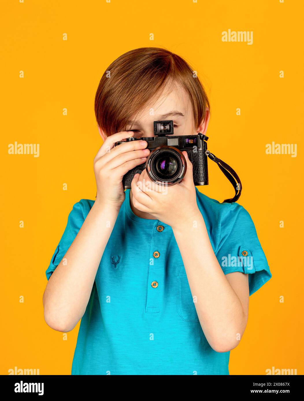 Teen boy looks through a vintage camera and trying the photographer ...