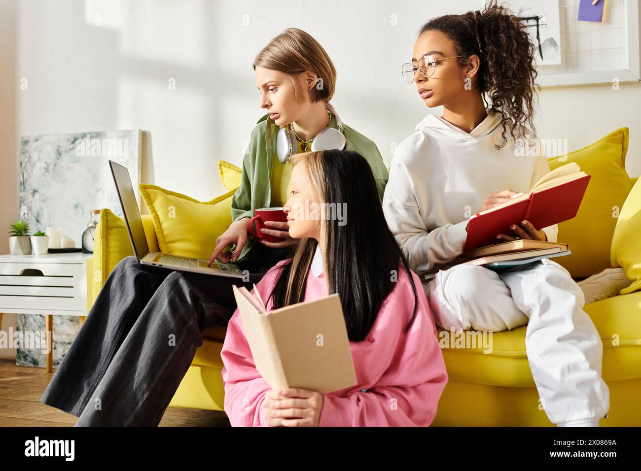 Three teenage girls of different races sit on a couch, absorbed in ...