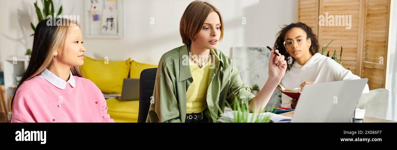 A group of interracial teenage girls sitting around a laptop, studying ...