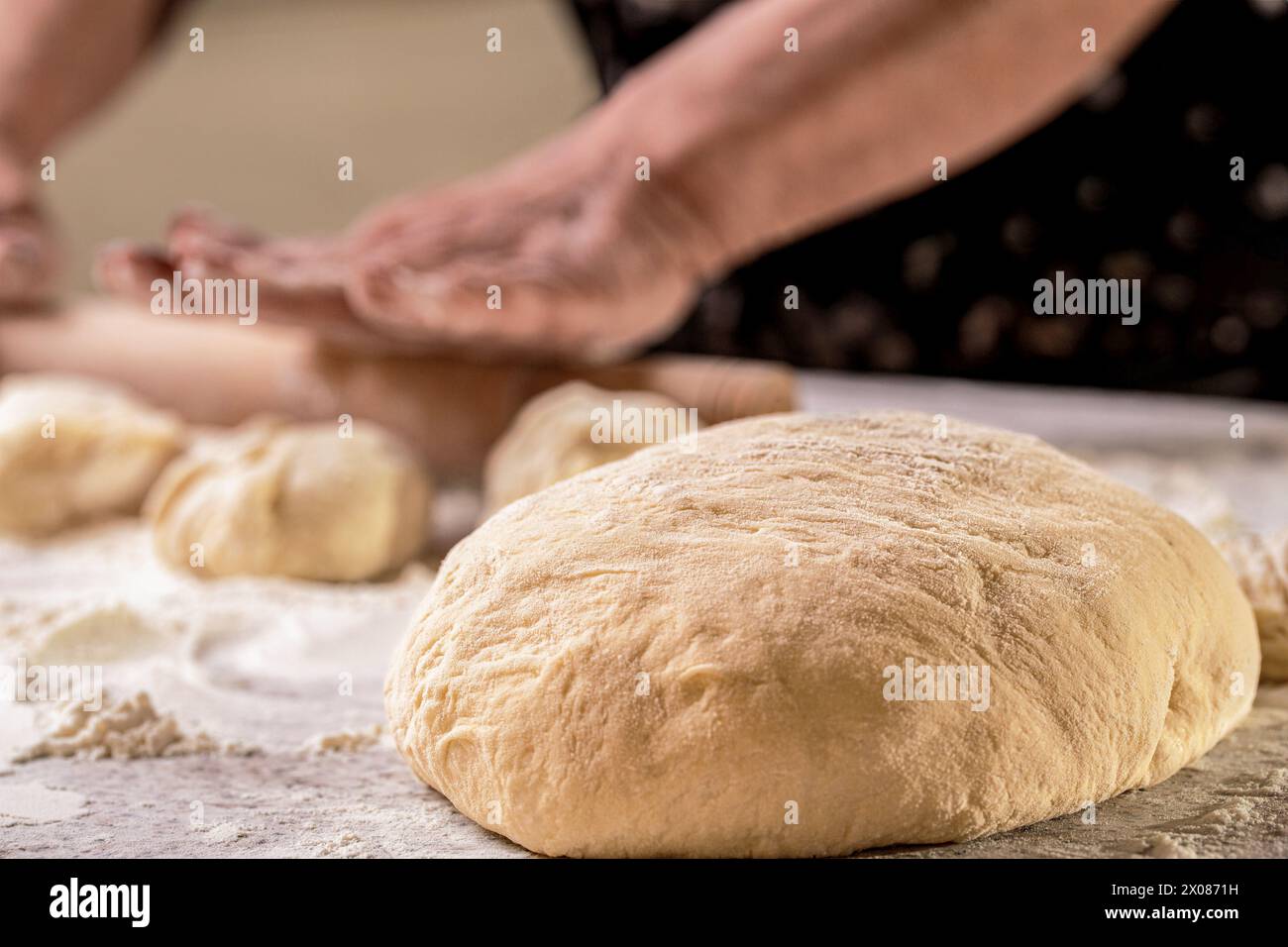 Dough close-up. Hands baking dough with rolling pin on wooden table ...