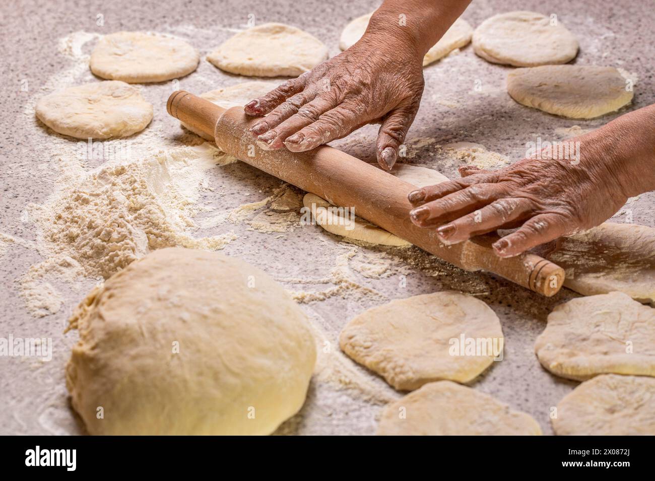Hands baking dough with rolling pin on wooden table. Old woman hands ...