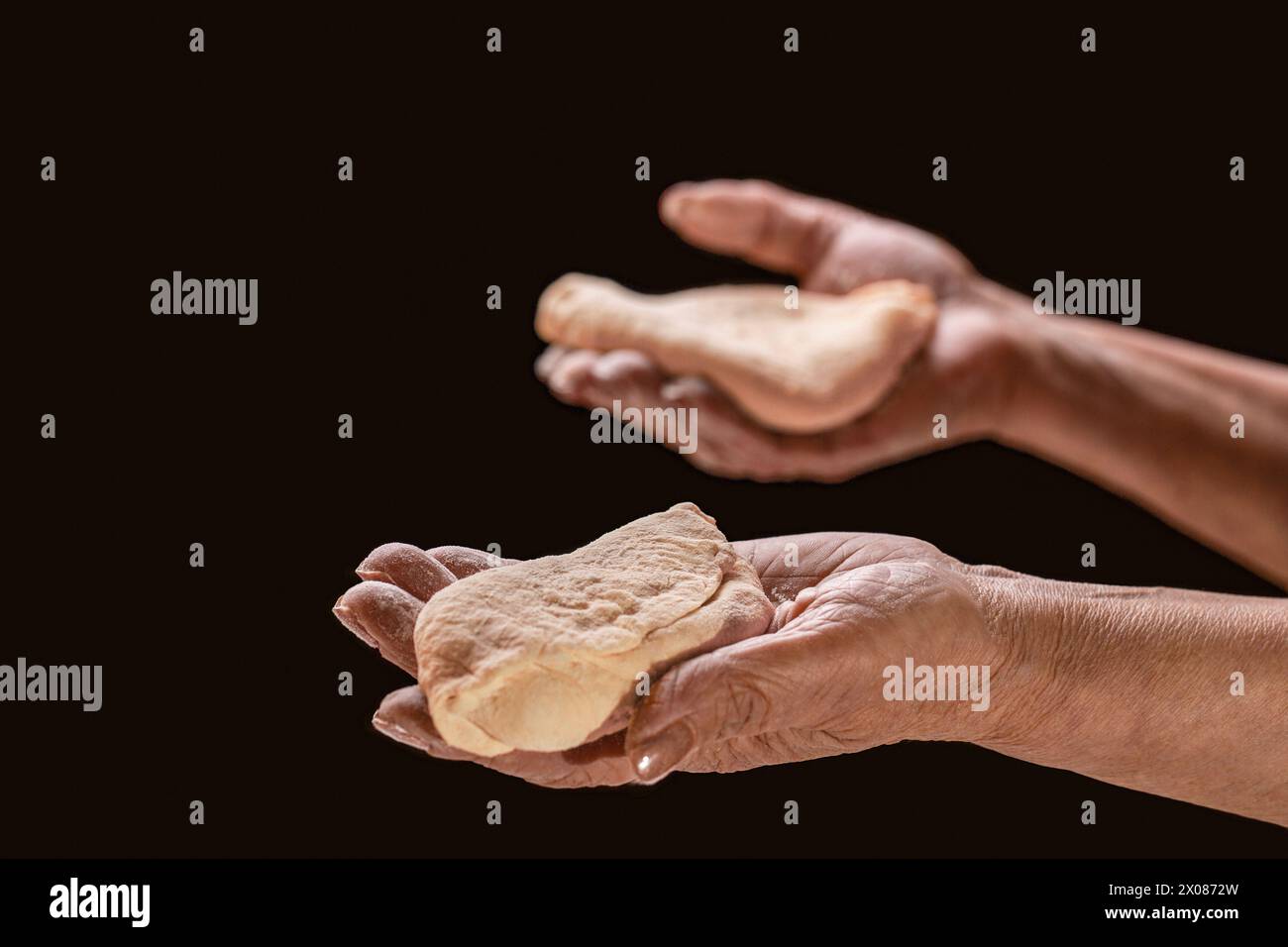 Old female hands holding a brown loaf of bread. Helping hand sharing ...
