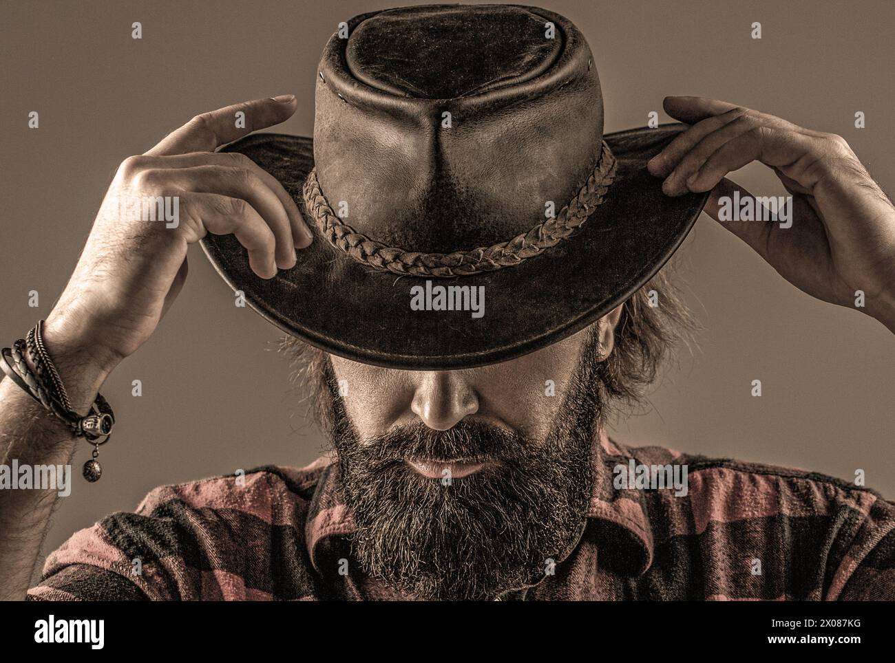Cowboy style. Handsome young man adjusting his cowboy hat. Cowboys in ...