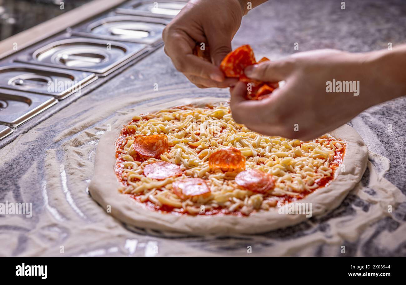 Cook hand makes a pizza, puts the sausage on top. Hand sprinkling ...