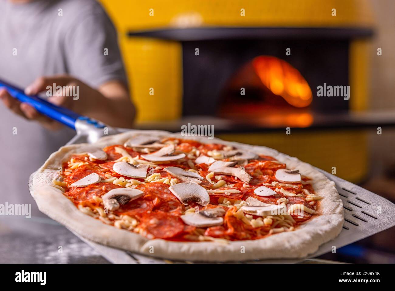 Chef placing the pizza in the hot oven to be baked. The chef prepares ...
