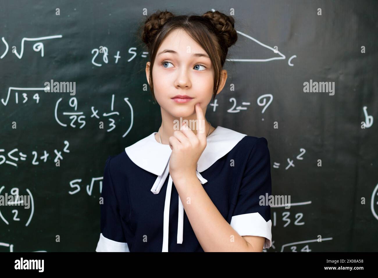 A teenage schoolgirl is thinking while standing at the blackboard, a 10 ...