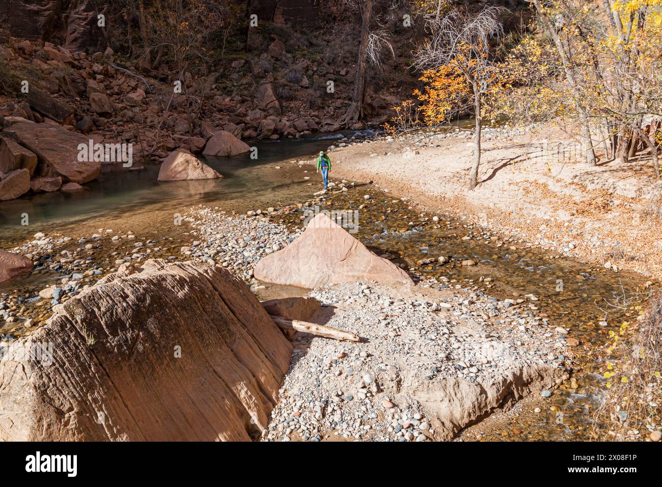 A hiker balances as they walk across a shallow section of the Virgin ...
