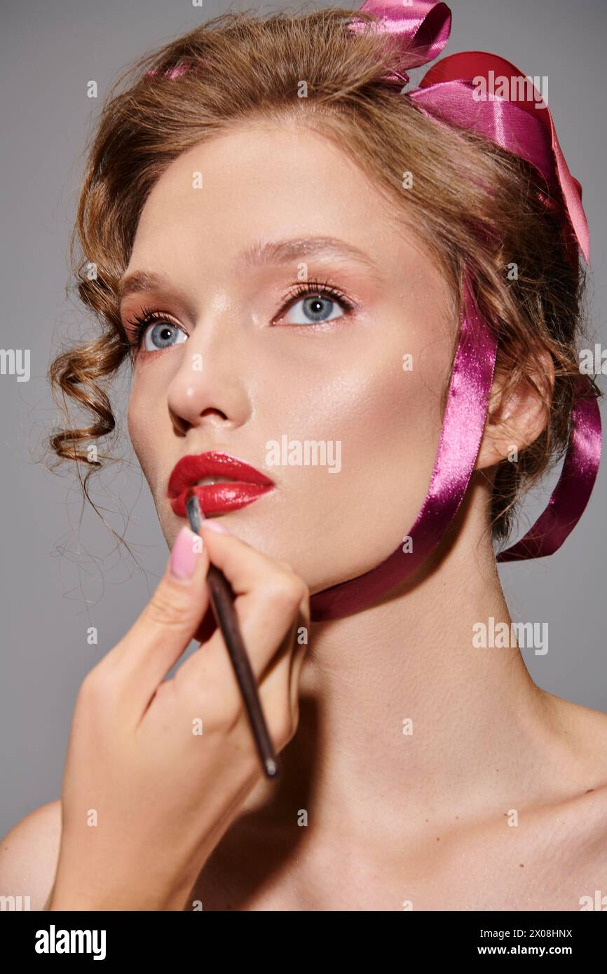 A classic beauty, a young woman poses elegantly with a pink bow perched ...