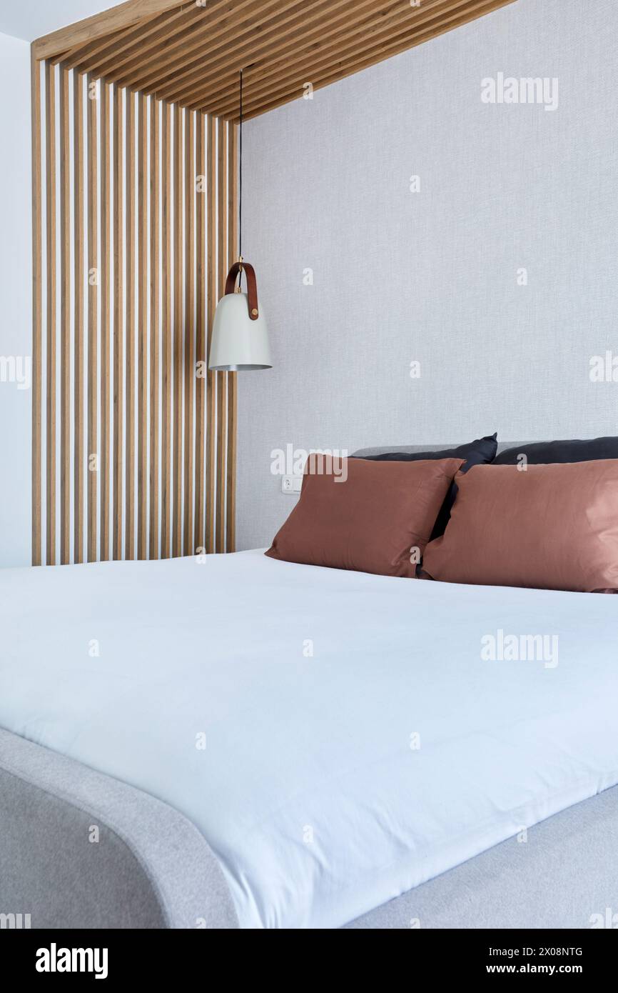 A stylish modern bedroom featuring a white sheeted bed, wooden slat ...