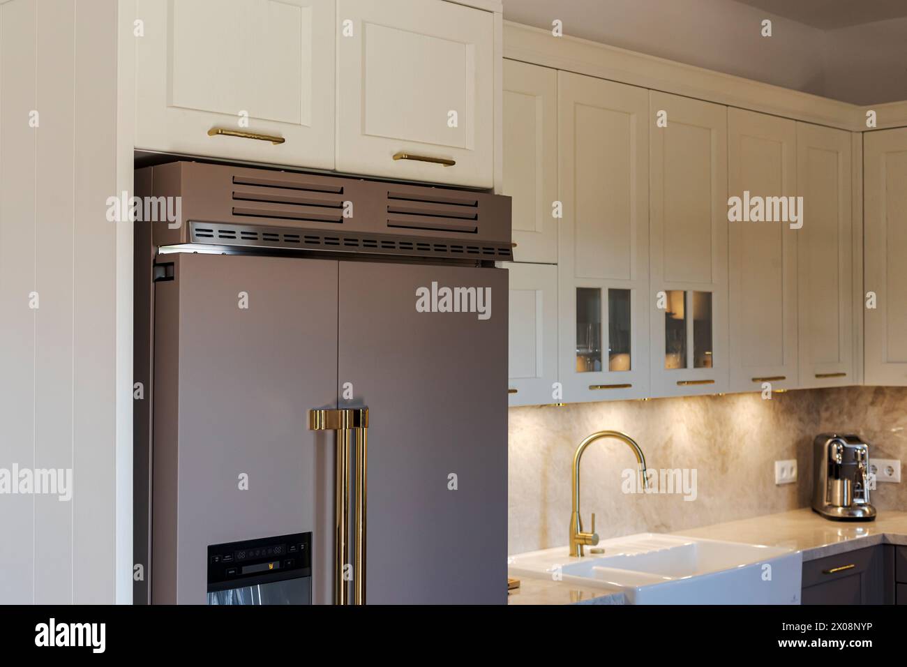 Elegant modern kitchen interior with gold accents and a grey fridge ...