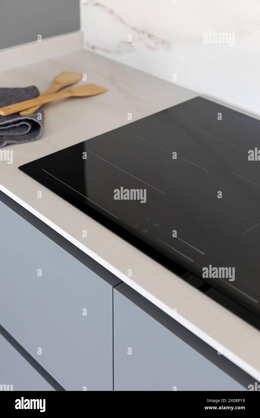 Modern induction cooktop in a clean kitchen with wooden utensils and a ...