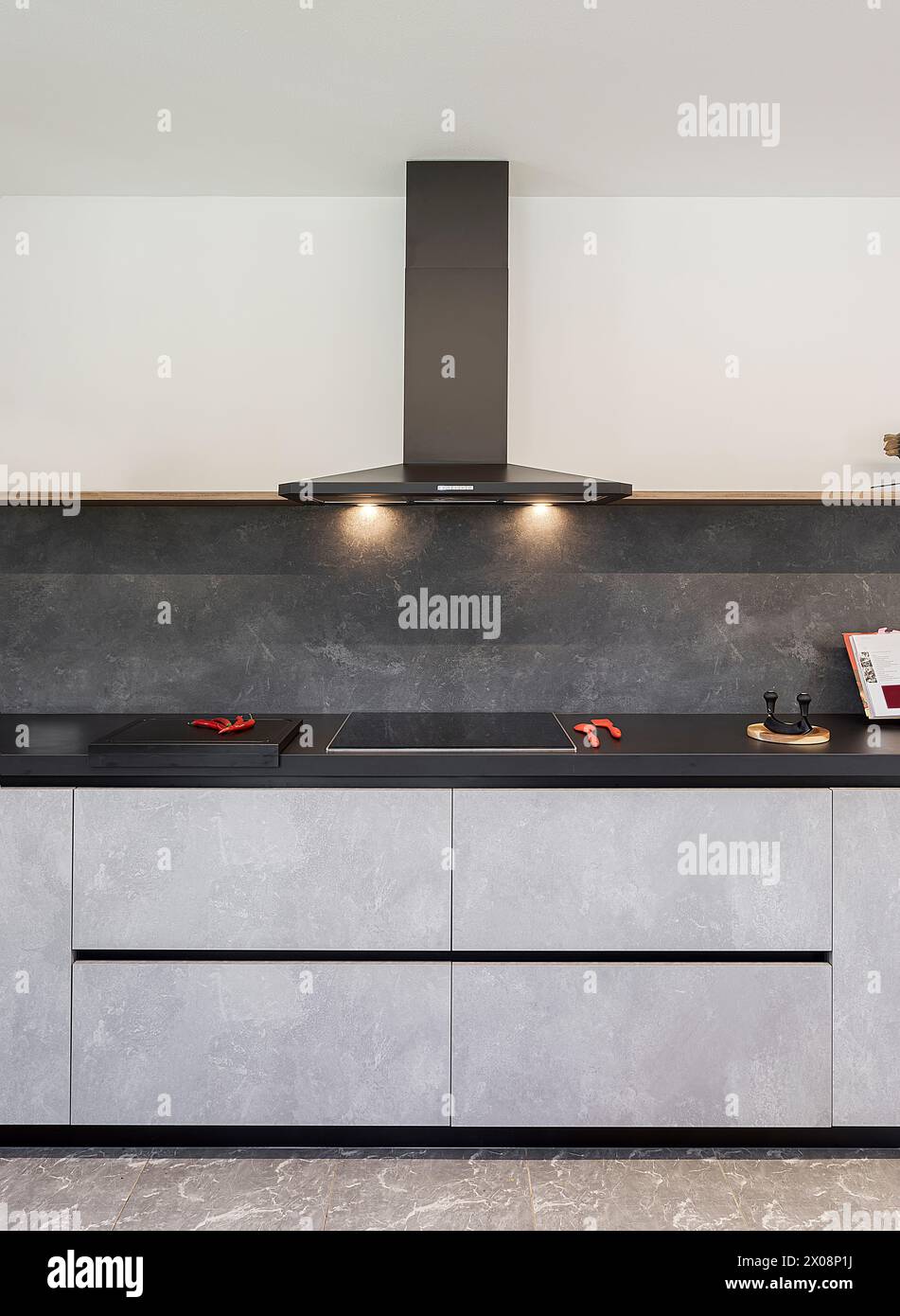 A stylish modern kitchen featuring a sleek black countertop with ...