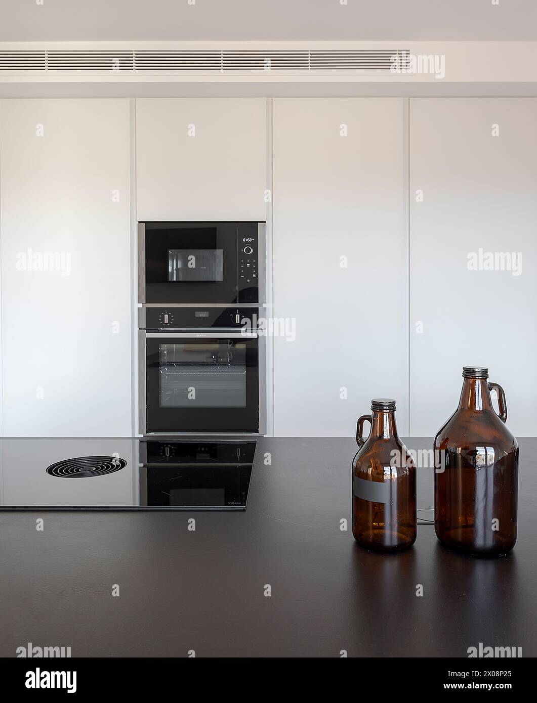 A modern kitchen interior with sleek built-in appliances and two amber ...