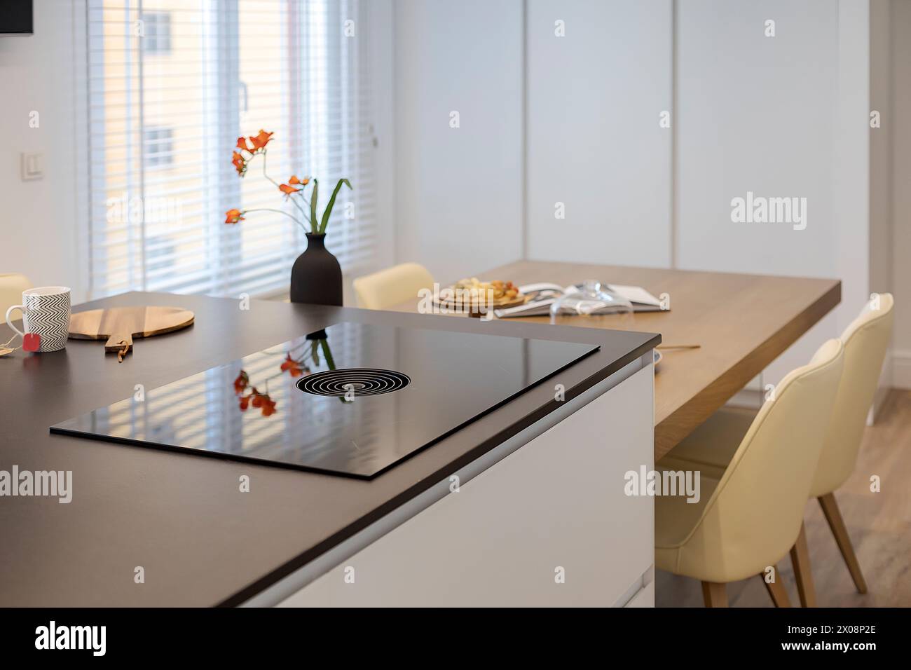 Modern kitchen interior with induction cooktop and dining table set ...