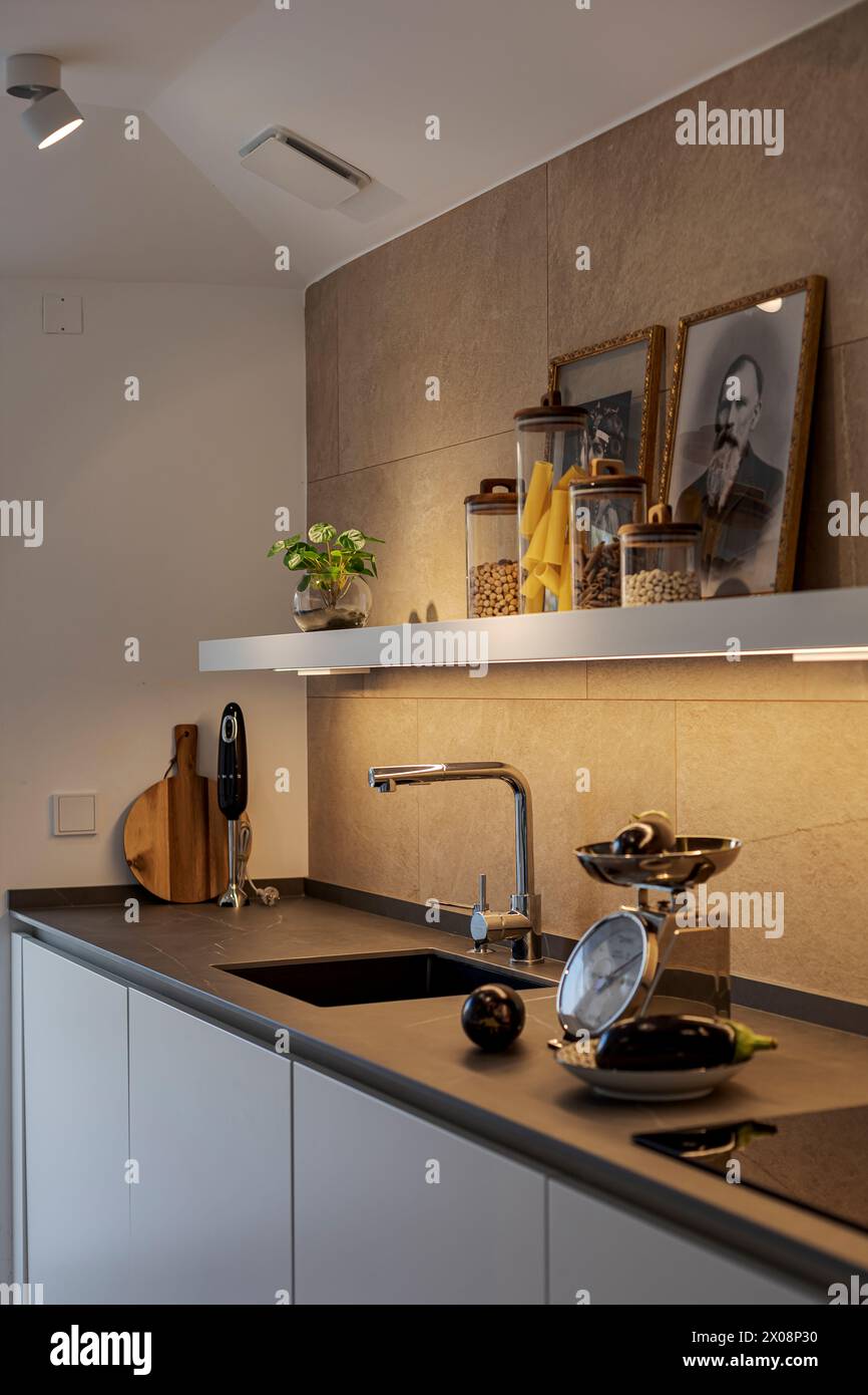 A stylish modern kitchen featuring a sleek black countertop, framed ...