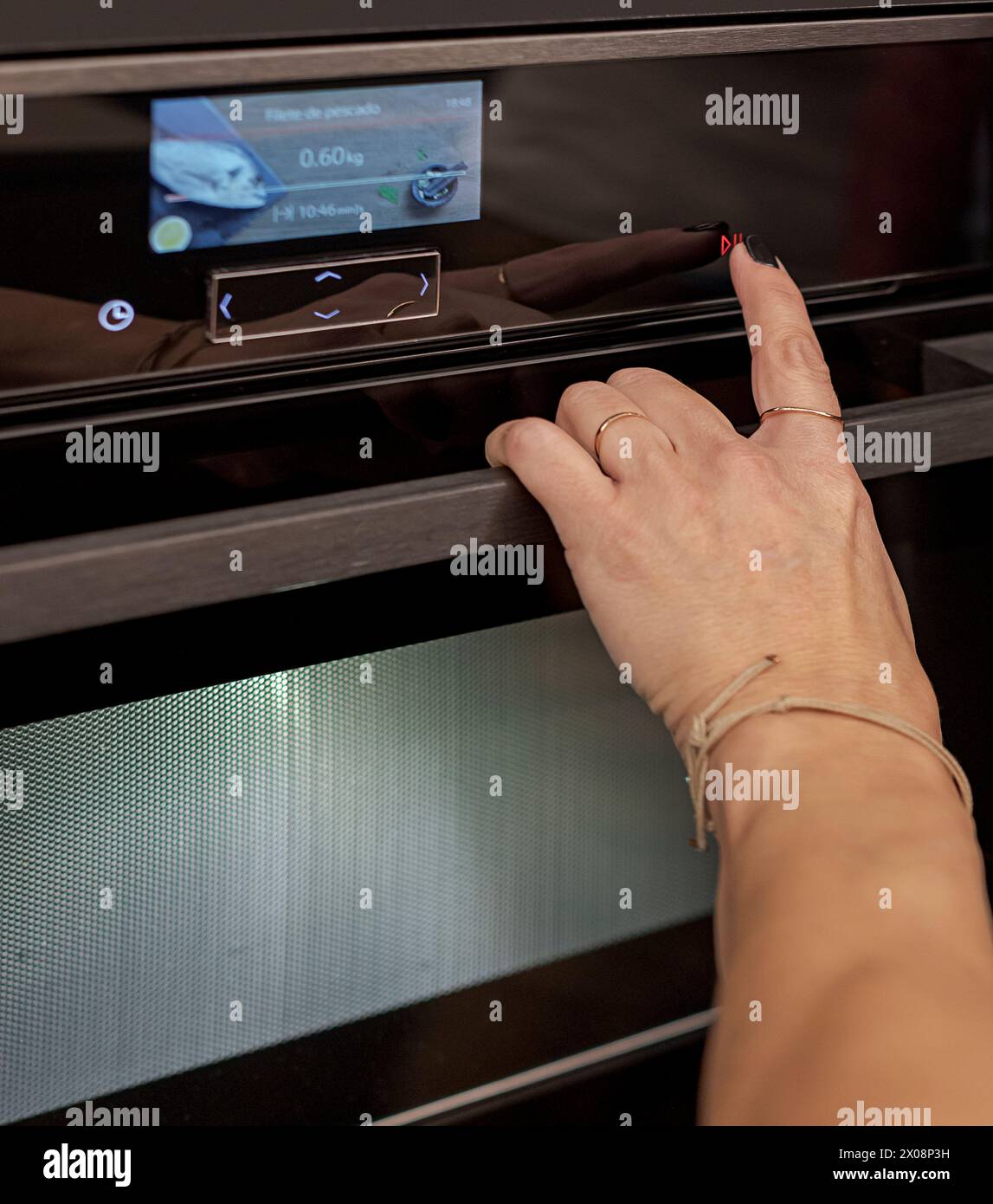 A hand operates a touchscreen display on a modern oven, selecting ...